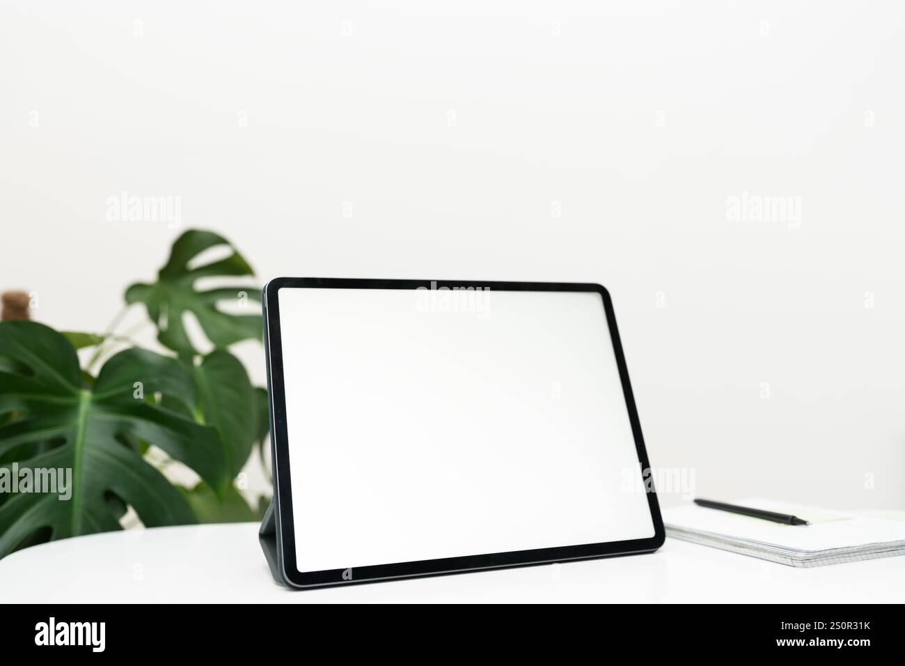 A neat office setup with a blank tablet screen, espresso, calculator ...
