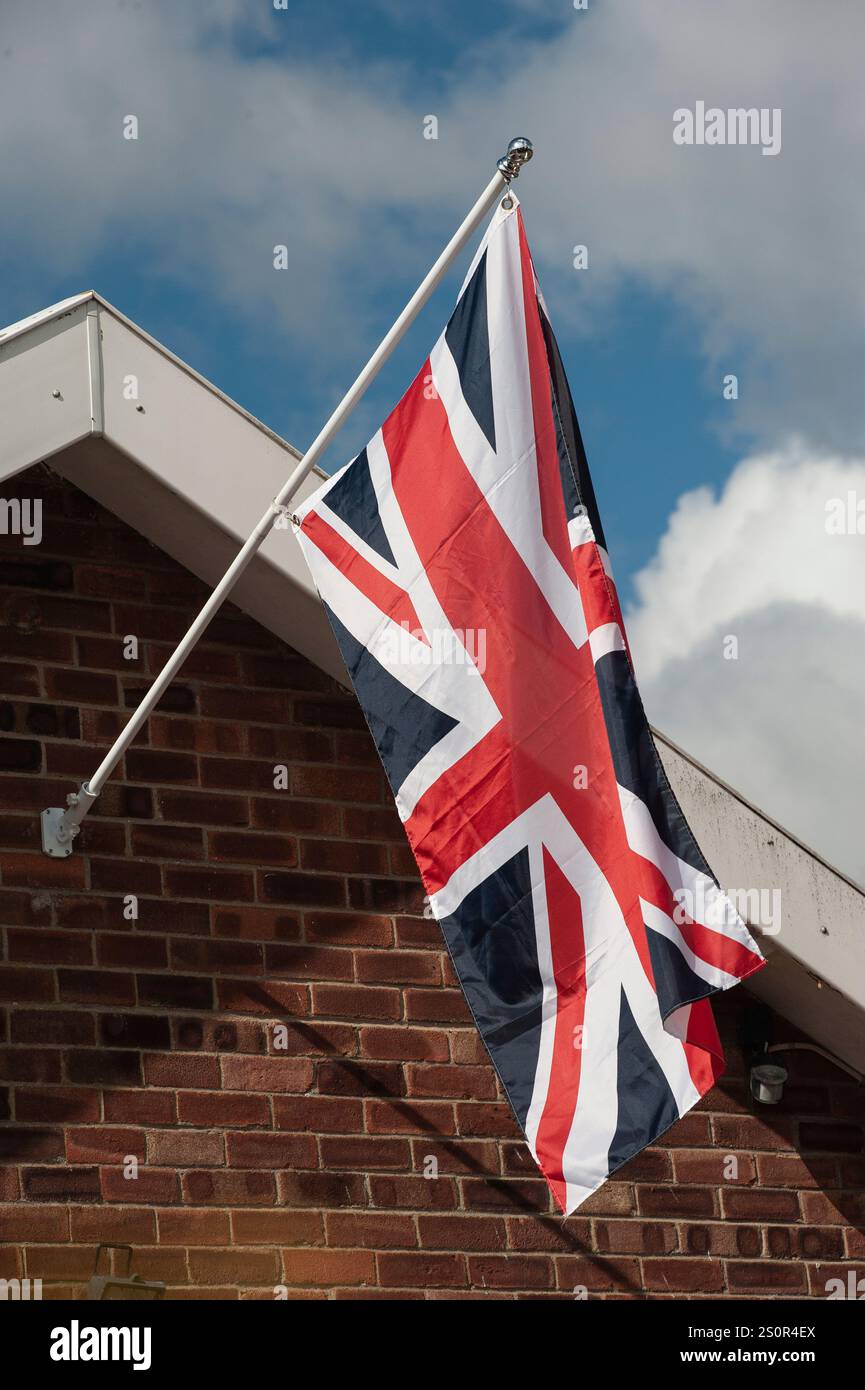 union jack flag flying of mast on eaves of bungalow, ellingham, norfolk ...