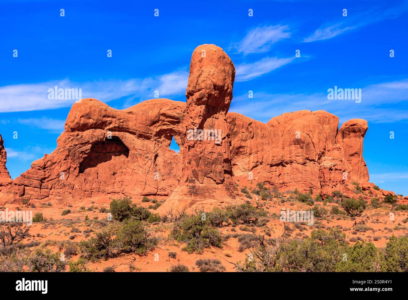 A large rock formation with a hole in the middle. The sky is blue and ...