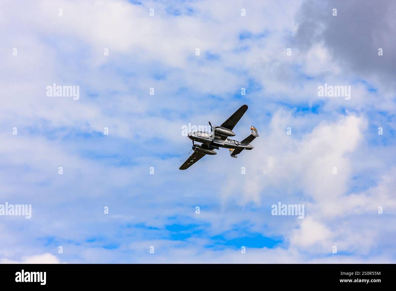 A small plane is flying through a cloudy sky. The sky is mostly blue ...