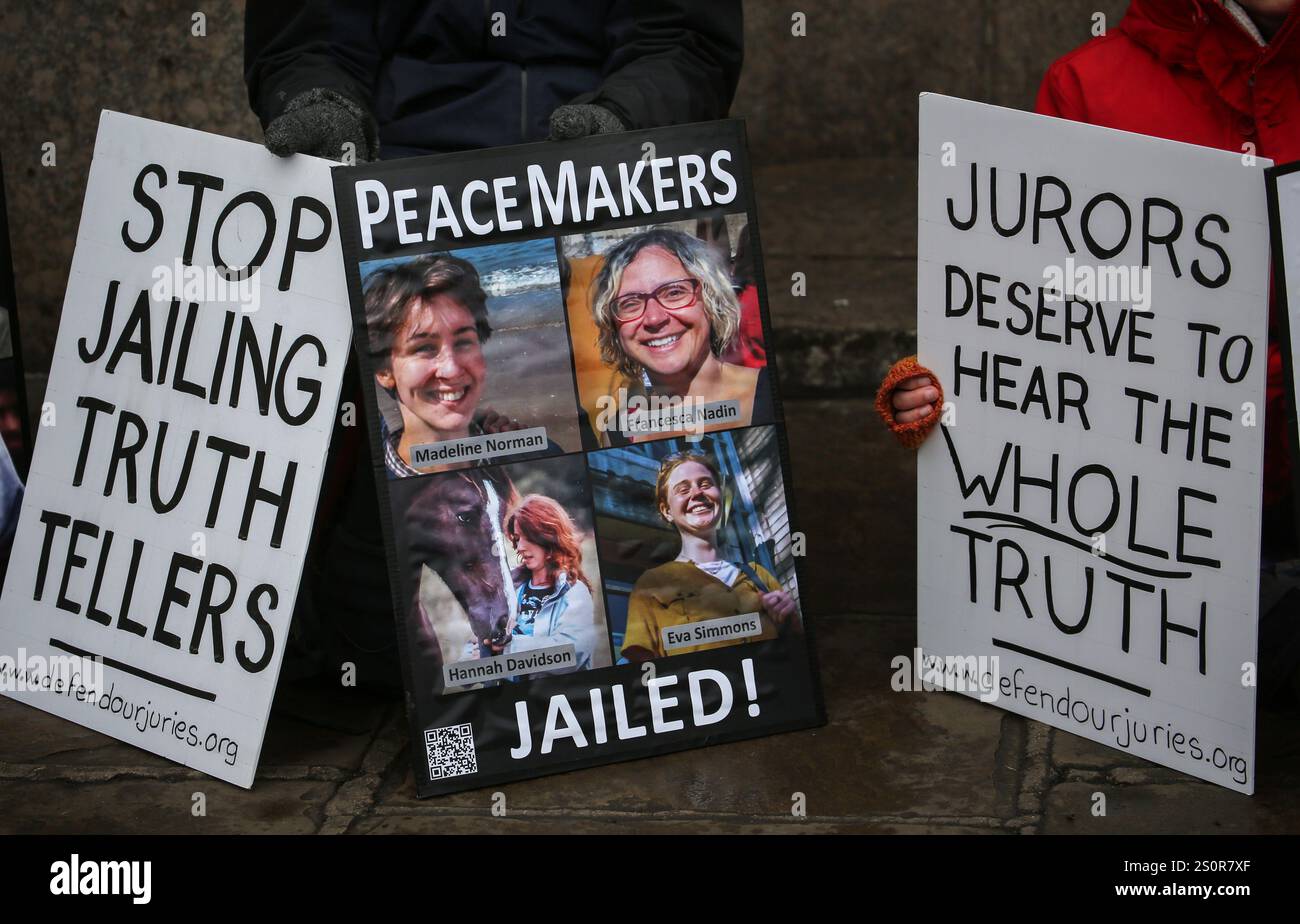A supporter of Defend Our Juries holds a placard showing photos of four ...