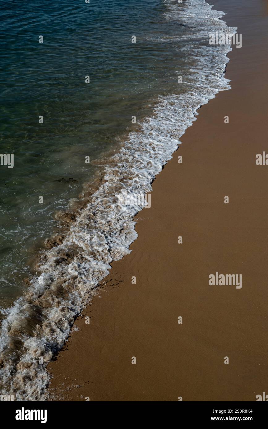 The shoreline stretches endlessly, where the rhythmic waves gently meet ...