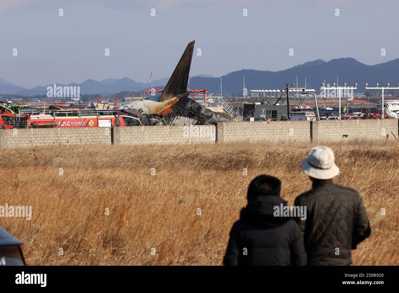 People watch as firefighters and rescue team members work at Muan ...