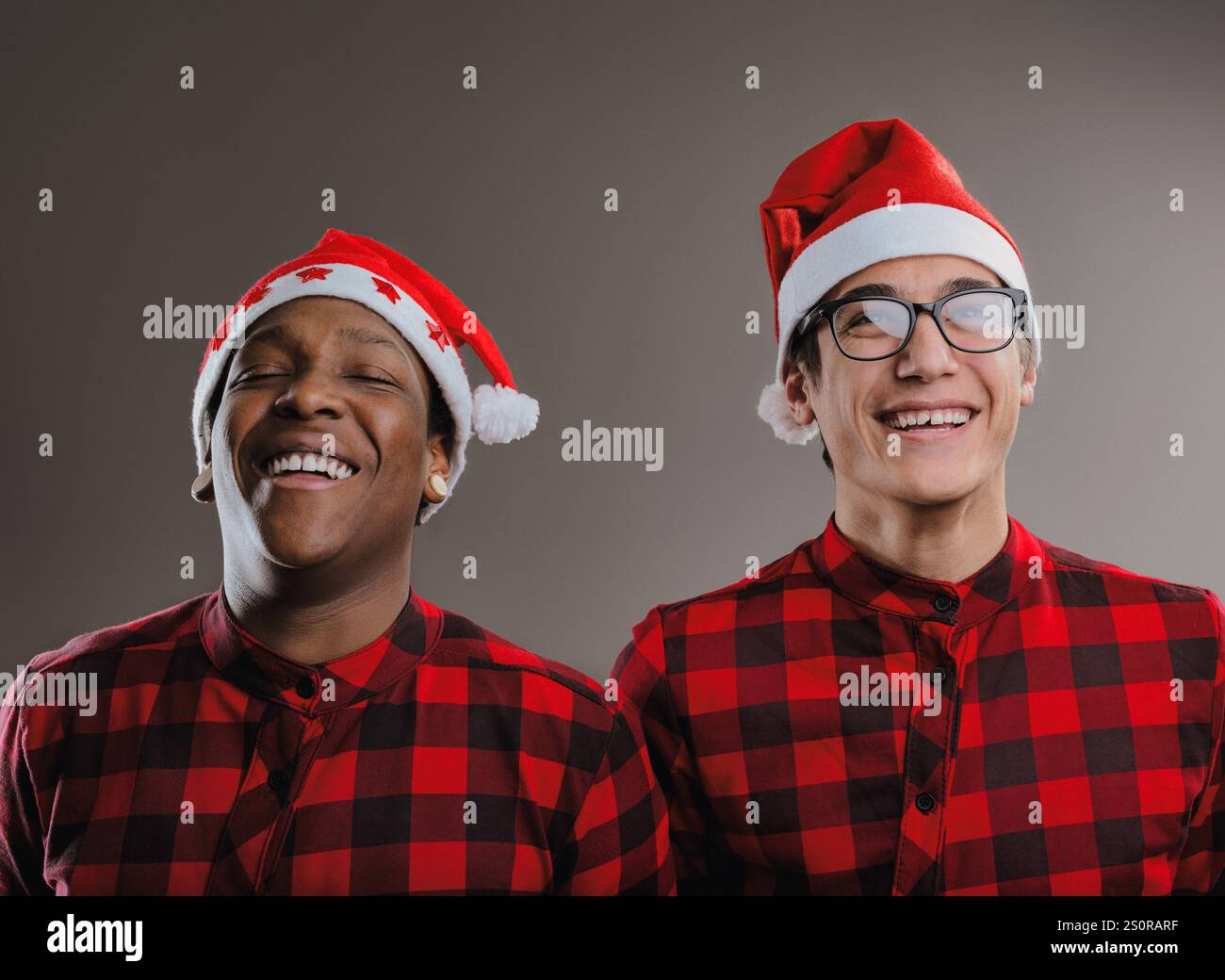 Two cheerful young men wearing matching red and black checkered shirts ...