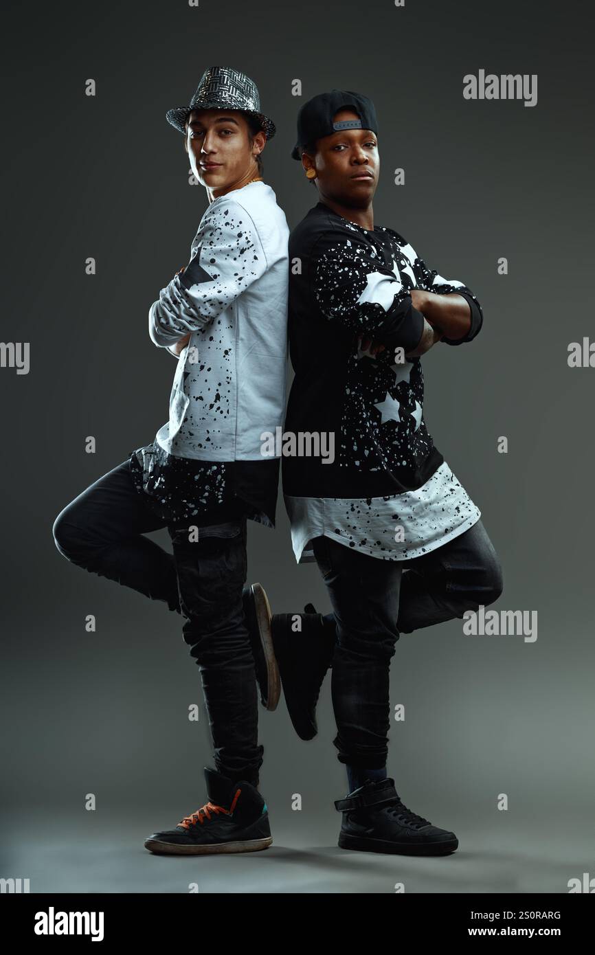 Two young male breakdancers posing confidently back to back with ...