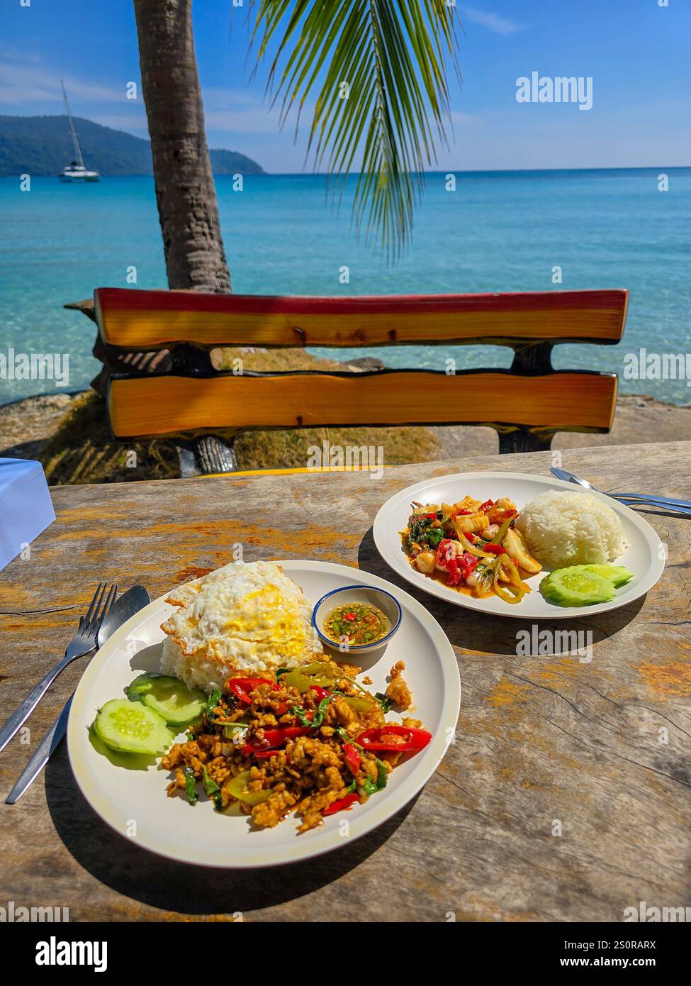 Savoring traditional Thai Phat kaphrao dishes at a beachfront table ...