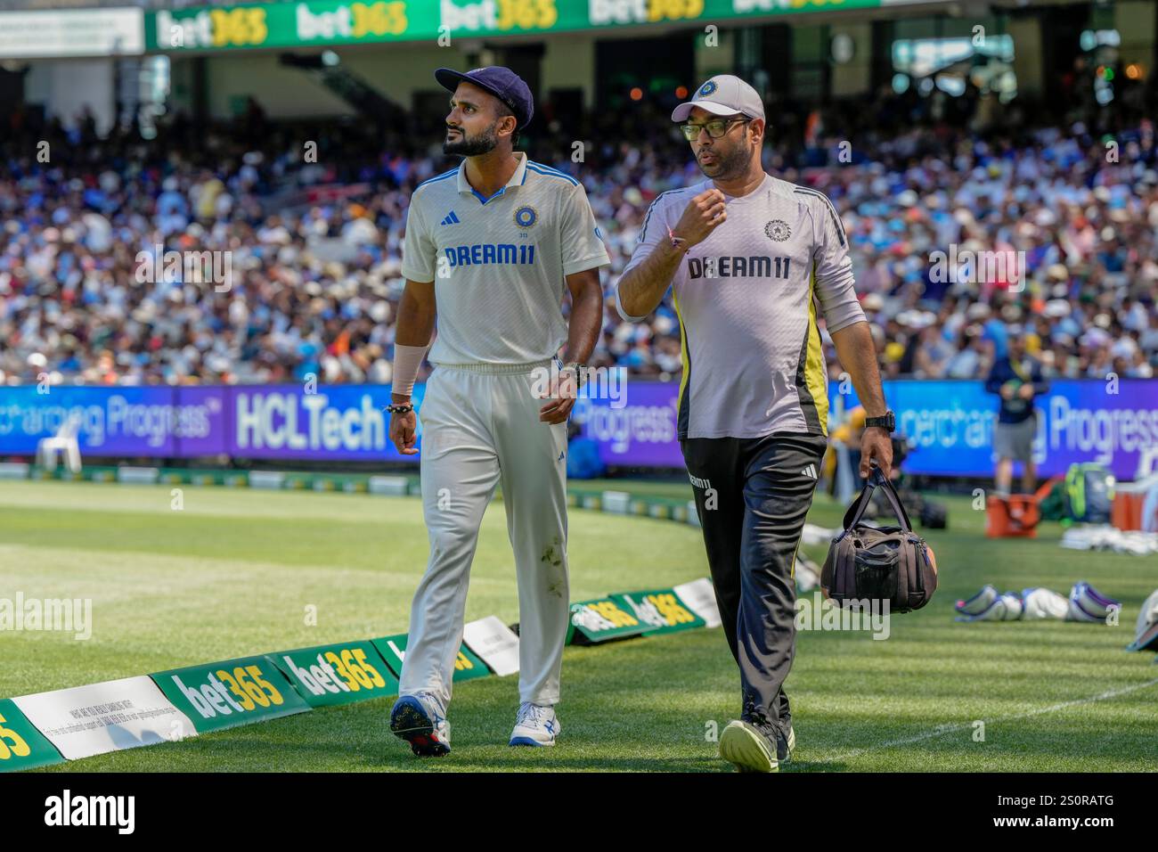India's Akash Deep walks off the field with team physio during play on ...