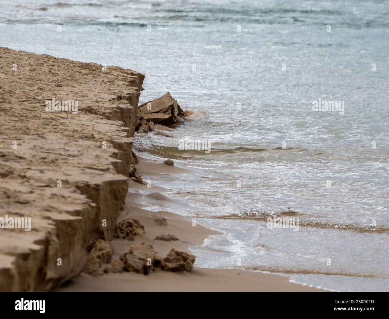 Sand eroding, crumbling from beach edge and clumps falling down as ...