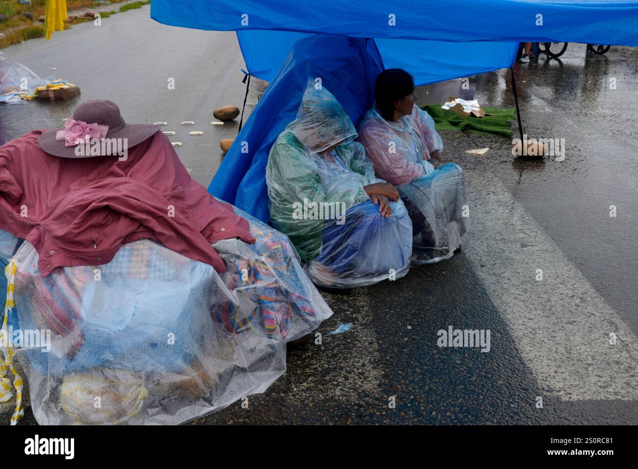 FILE - Street vendors take cover from the rain in Lauca N in the ...
