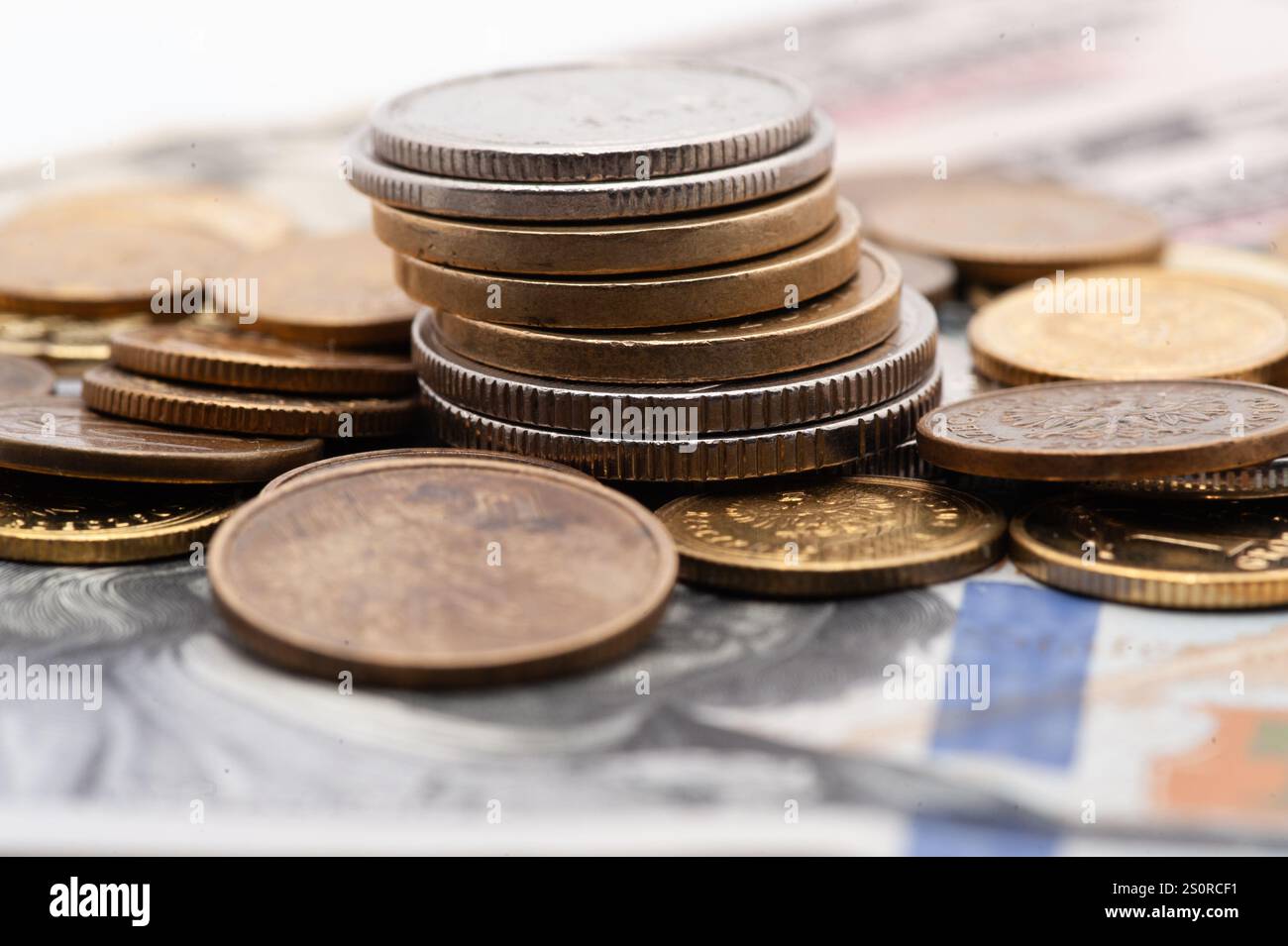 A stack of coins with a silver coin on top. The coins are of different ...