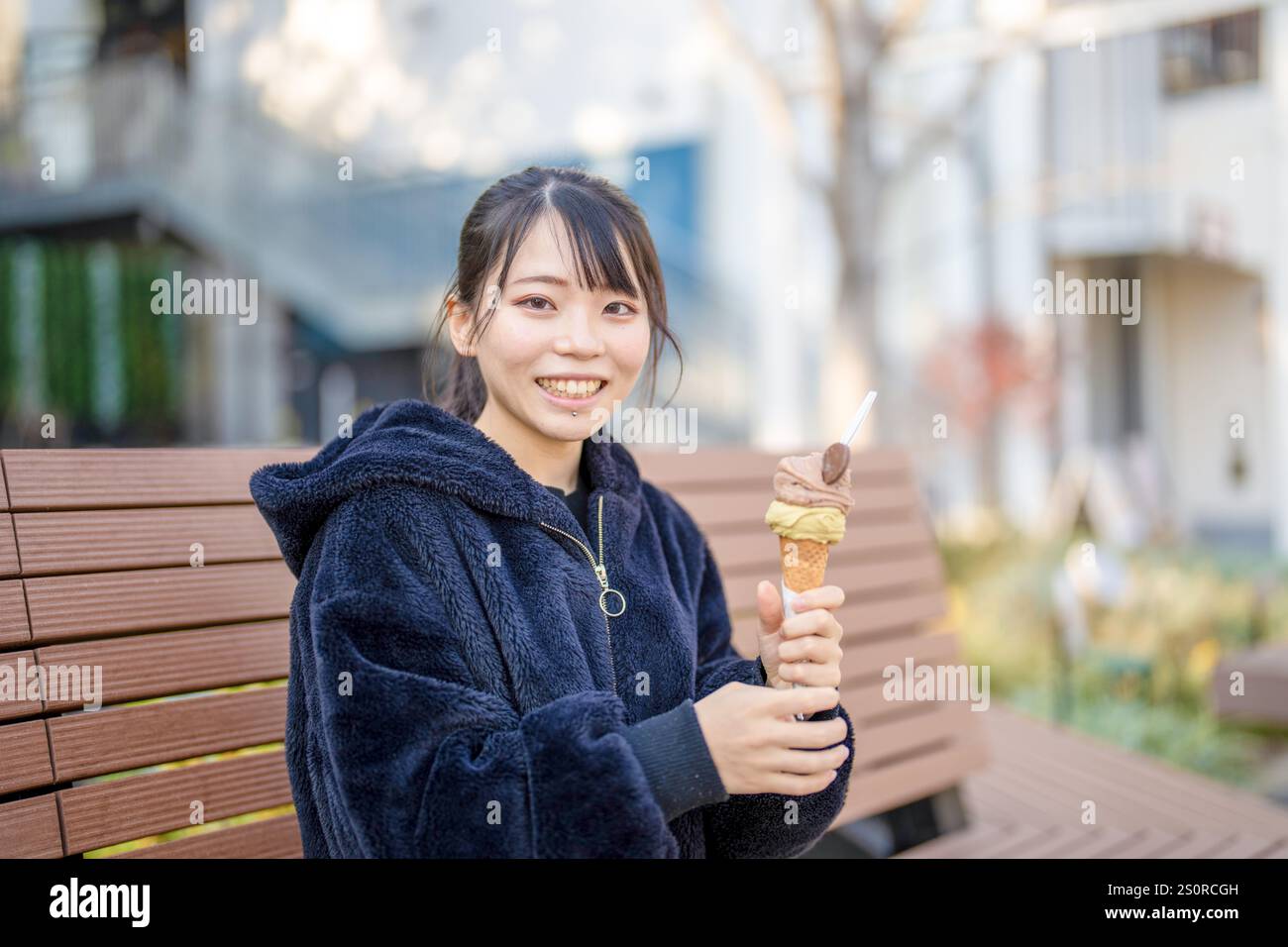Cute woman in her early twenties eating gelato deliciously on bench in ...