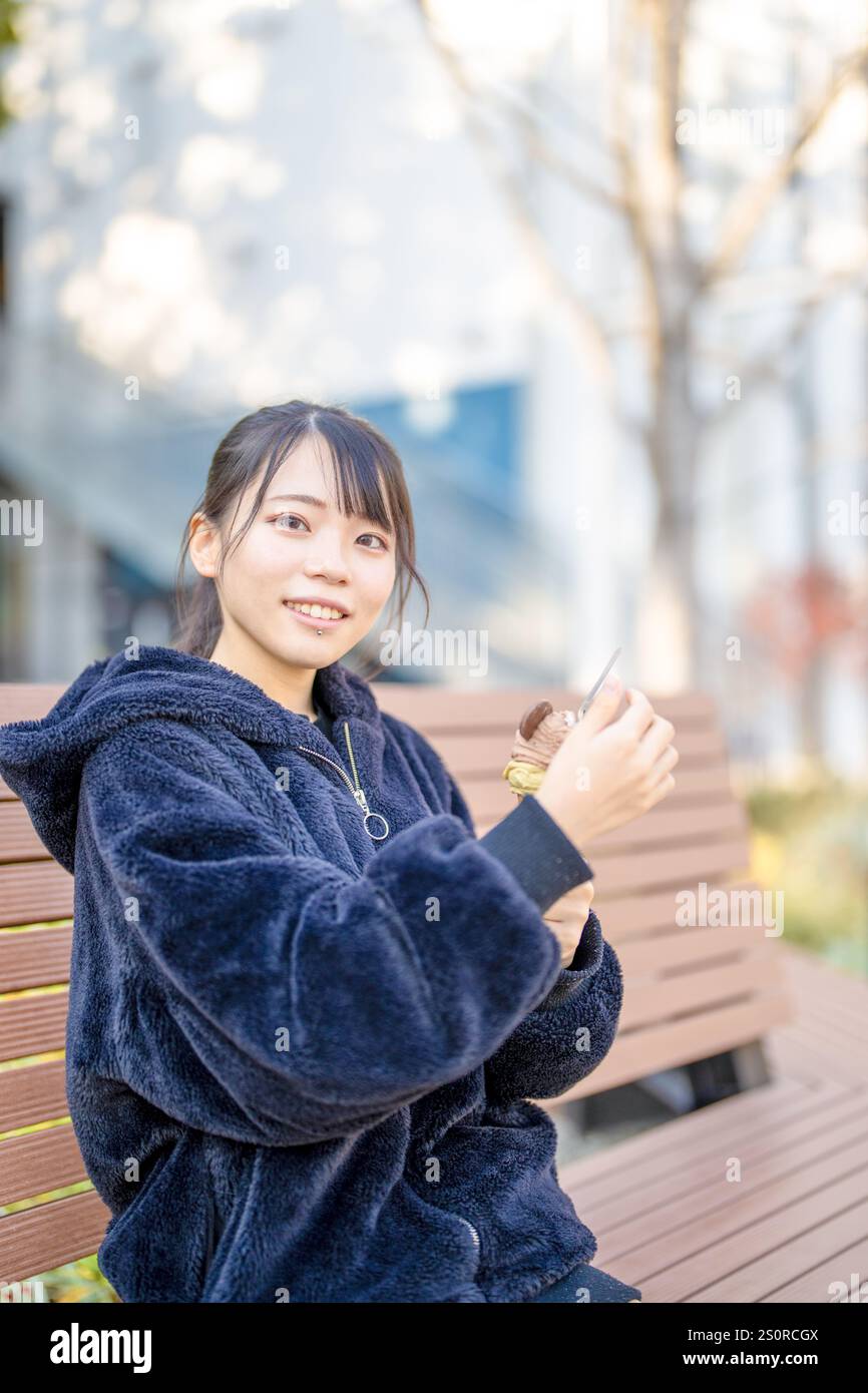 Cute woman in her early twenties eating gelato deliciously on bench in ...
