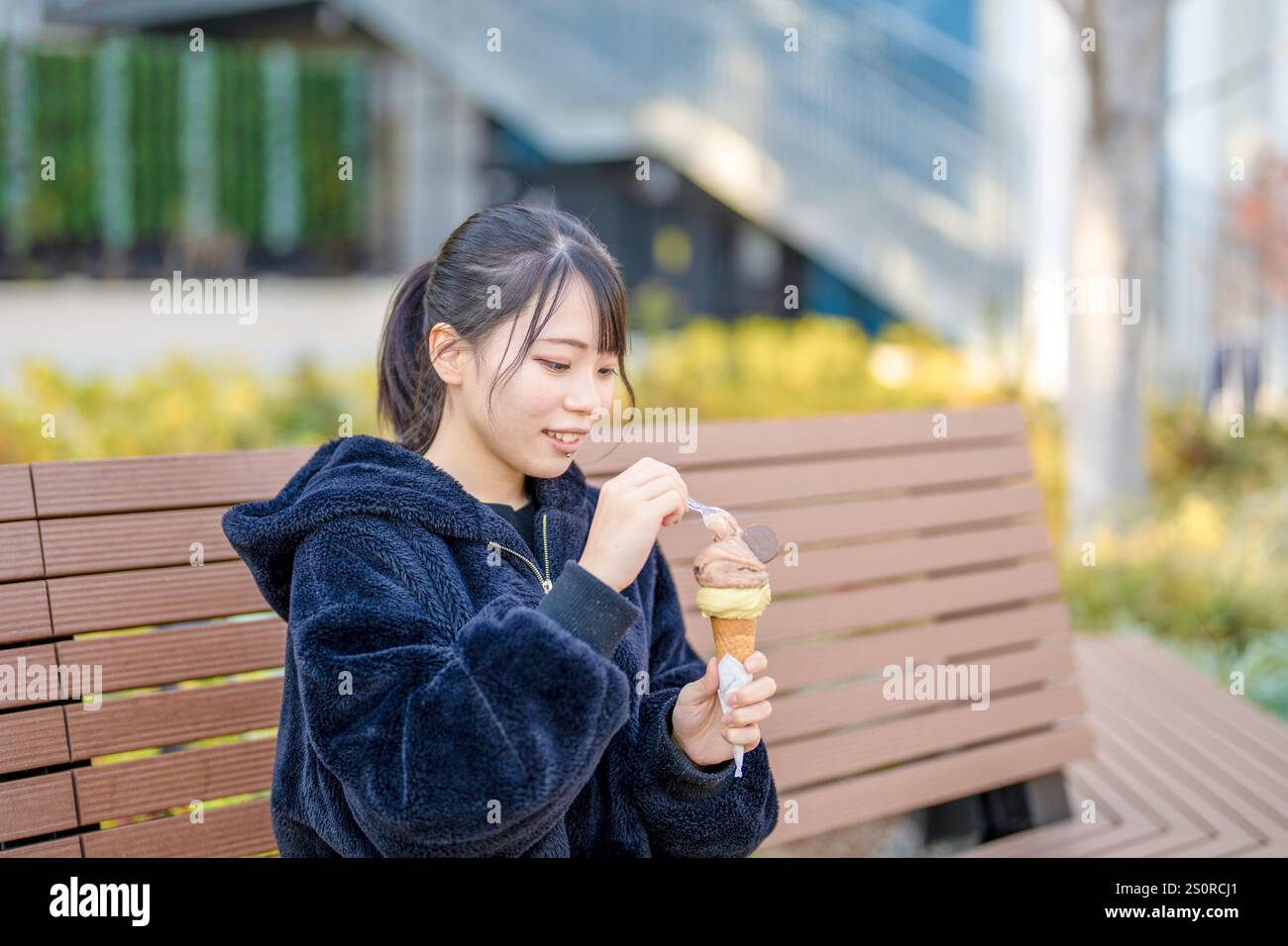 Cute woman in her early twenties eating gelato deliciously on bench in ...