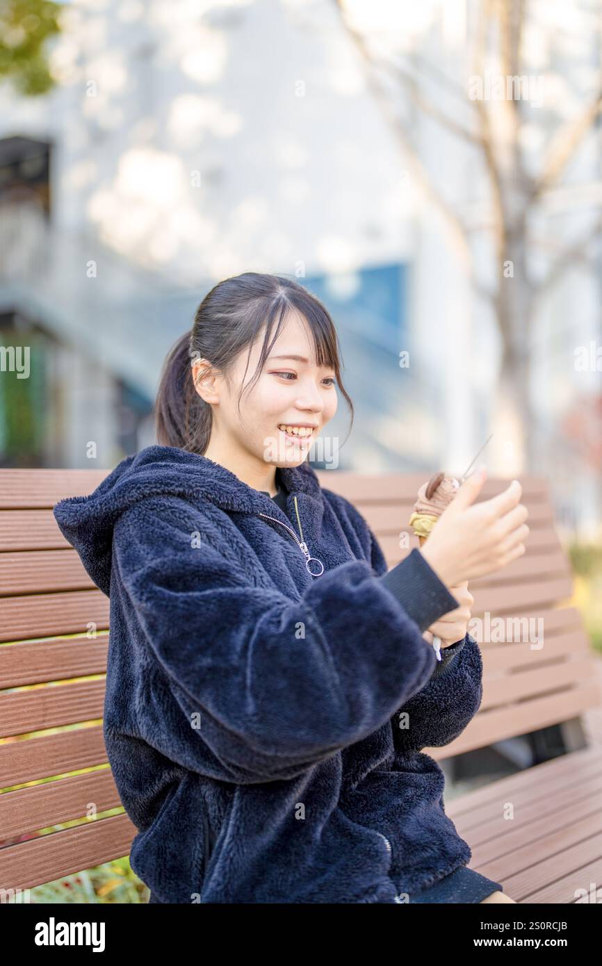 Cute woman in her early twenties eating gelato deliciously on bench in ...