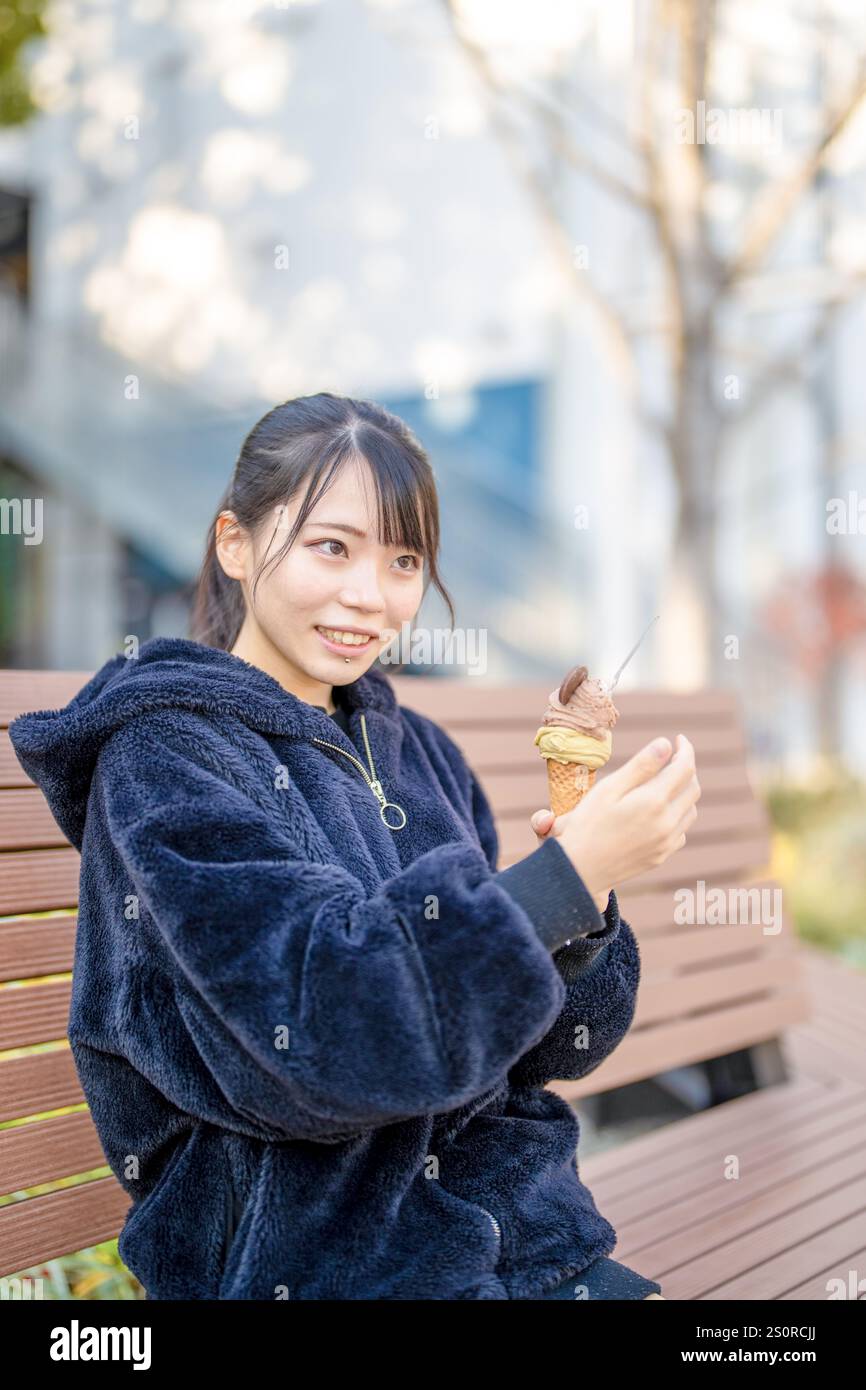 Cute woman in her early twenties eating gelato deliciously on bench in ...