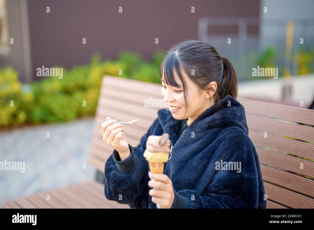Cute woman in her early twenties eating gelato deliciously on bench in ...