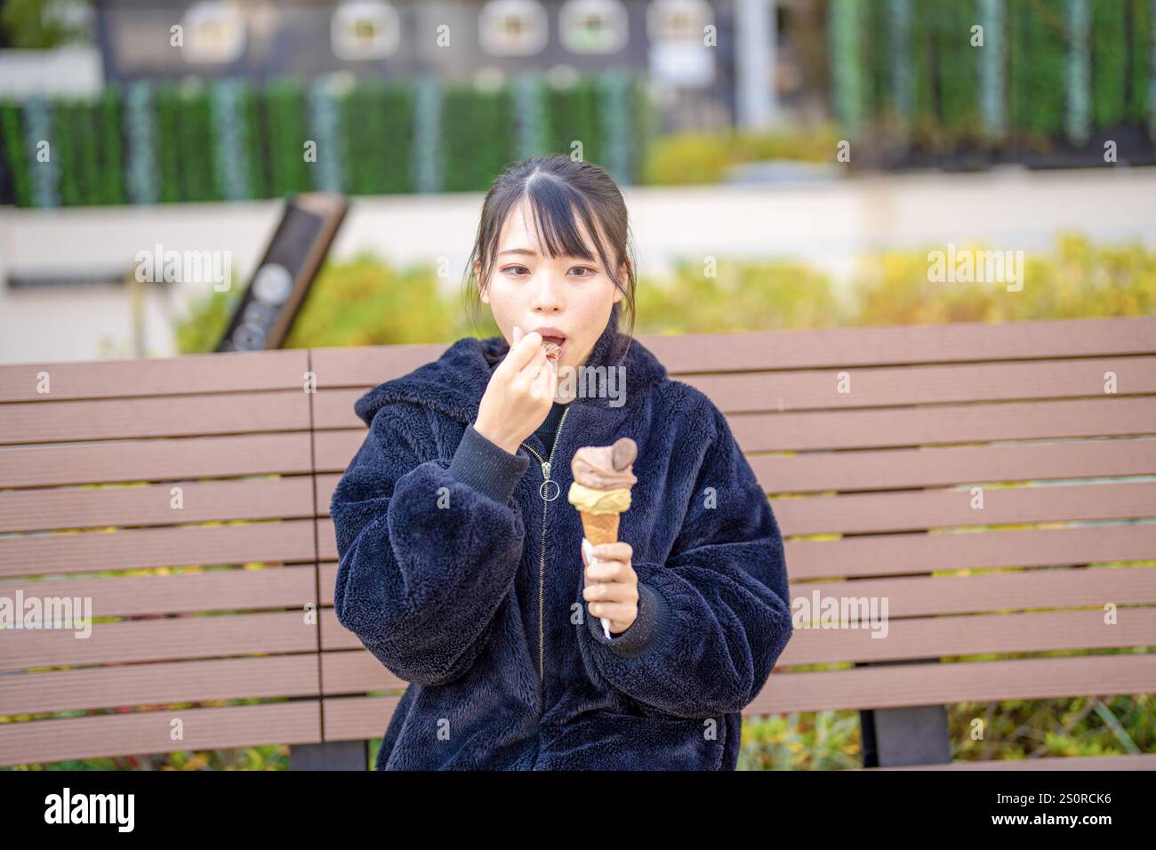 Cute woman in her early twenties eating gelato deliciously on bench in ...