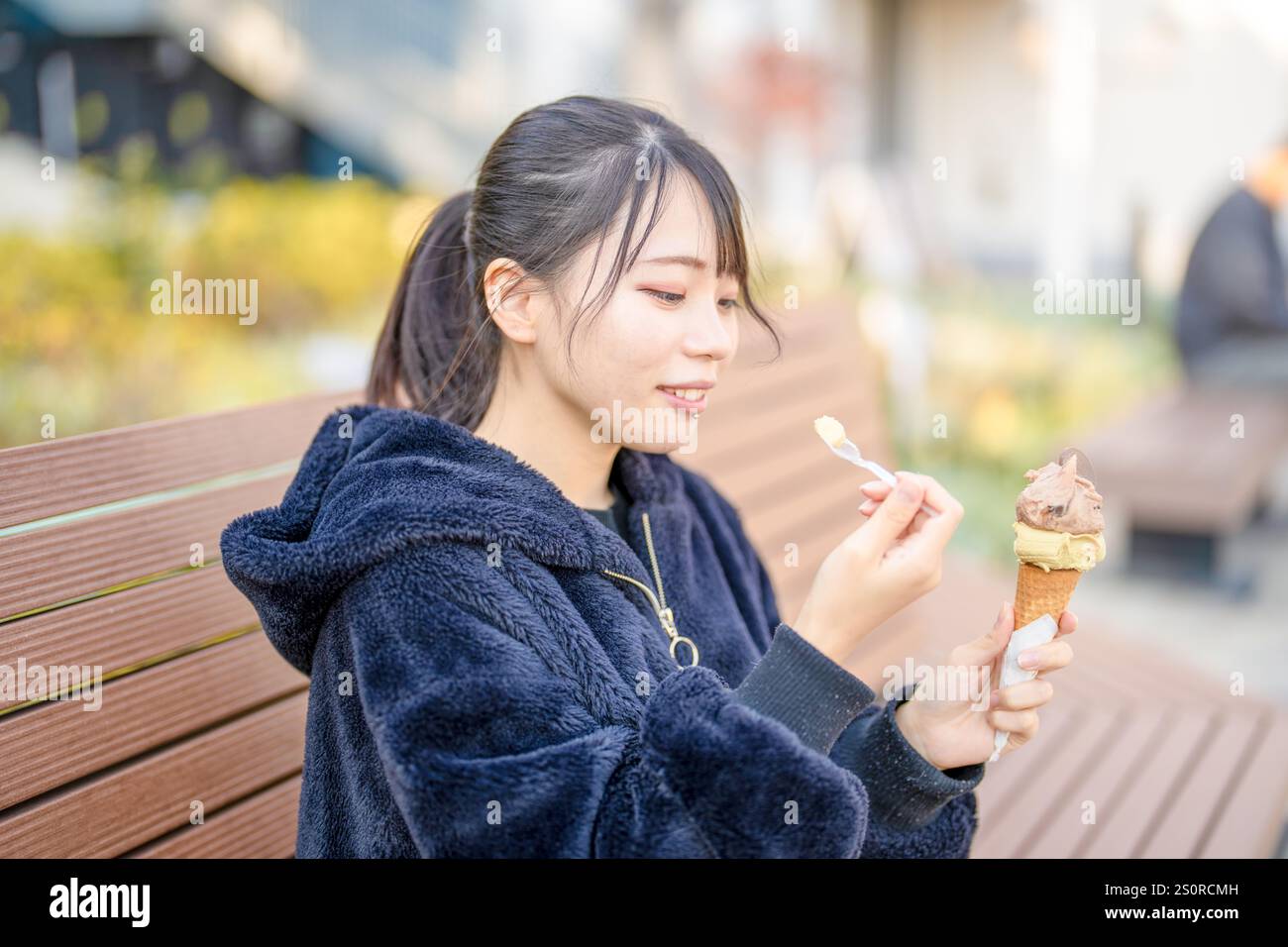 Cute woman in her early twenties eating gelato deliciously on bench in ...