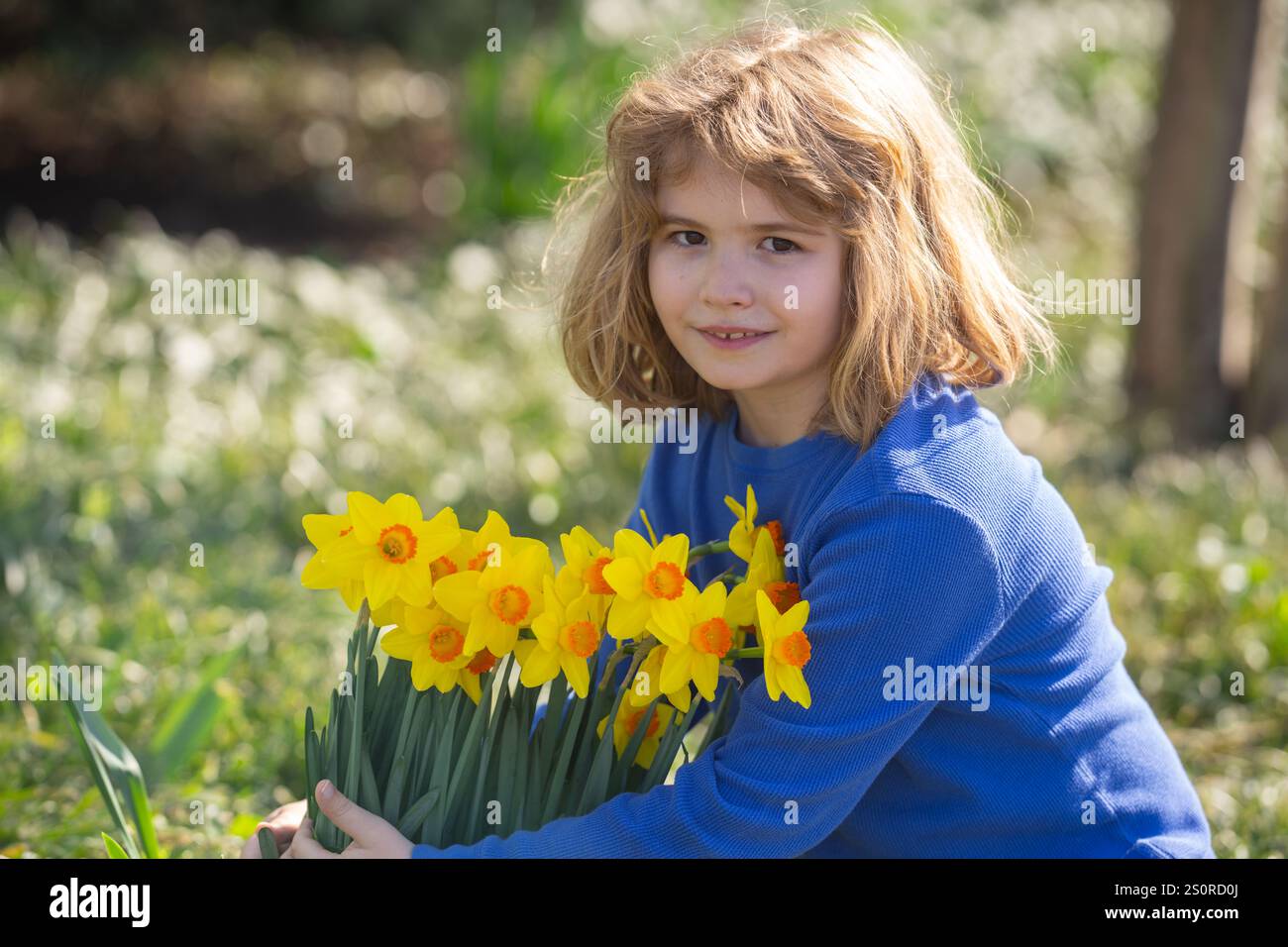 Little kid smelling spring narcissus flower outdoor. Pretty child boy ...
