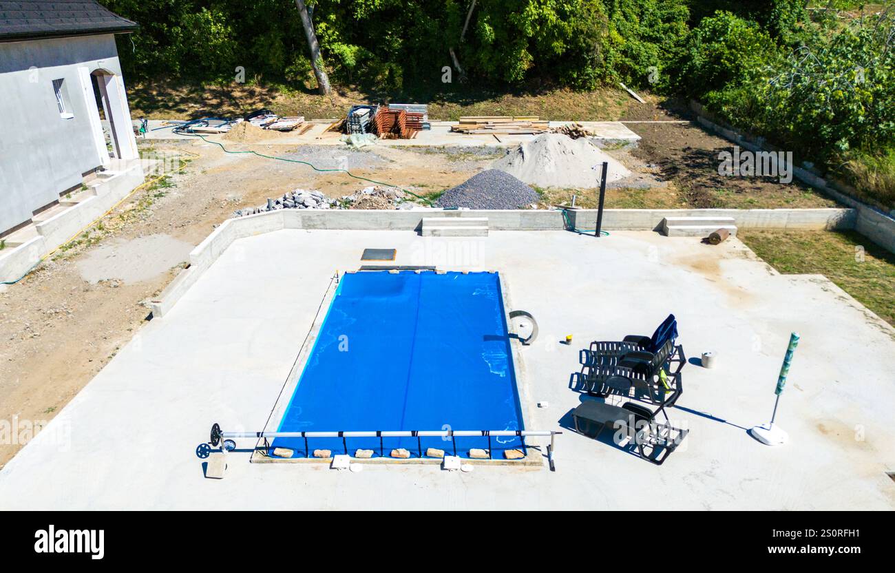 Swimming pool construction site with blue pool cover and equipment ...
