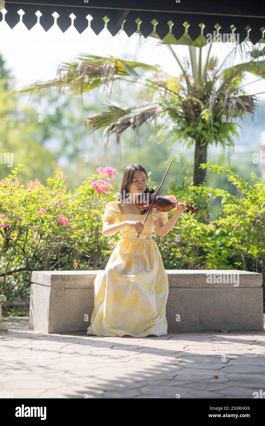 Twenty-something Chinese woman in yellow dress gracefully playing ...