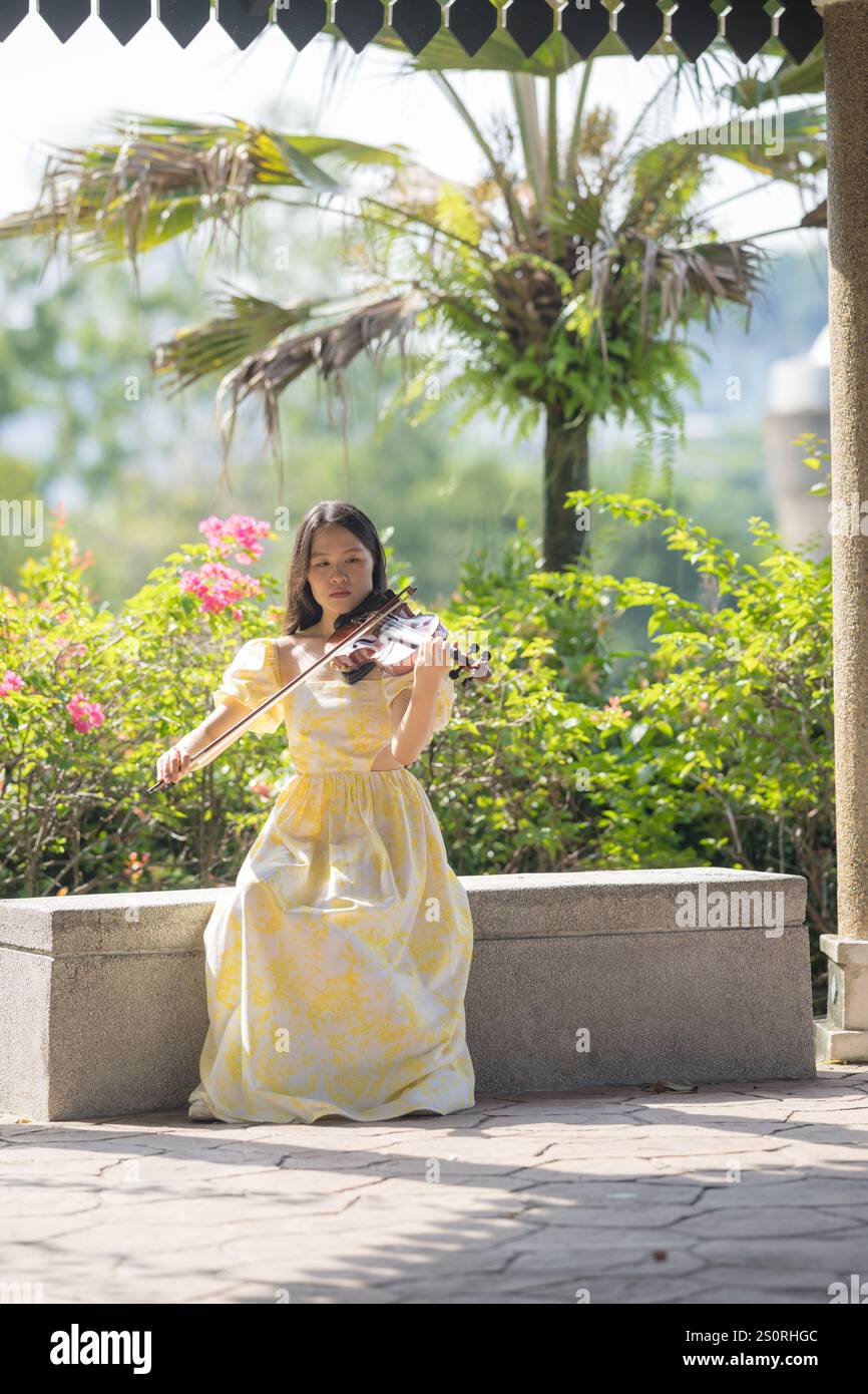 Twenty-something Chinese woman in yellow dress gracefully playing ...