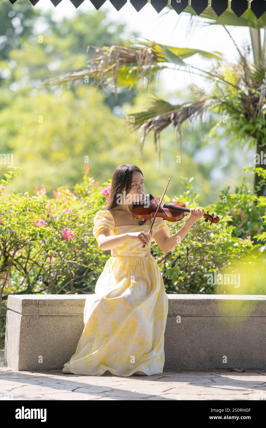 Twenty-something Chinese woman in yellow dress gracefully playing ...