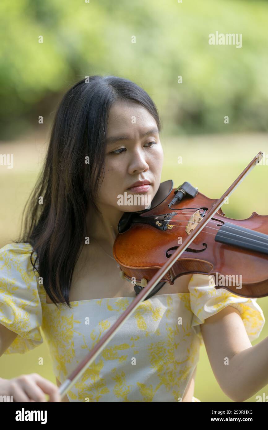 Twenty-something Chinese woman in yellow dress gracefully playing ...