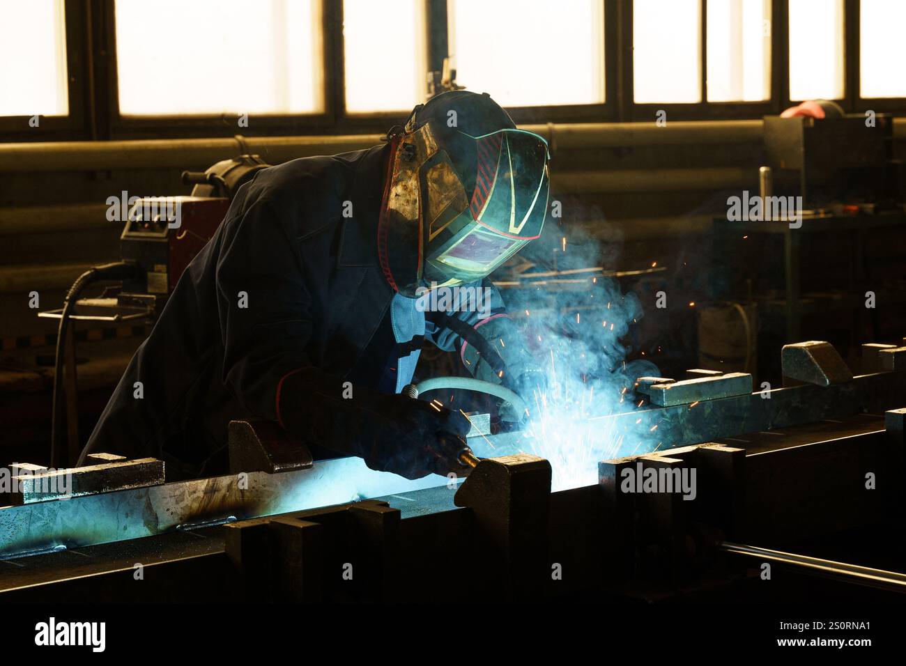 A dedicated welder focuses on a metal piece in a bustling workshop ...