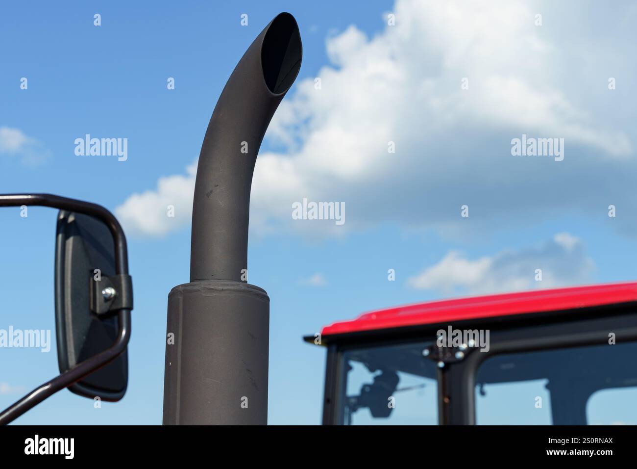 A close-up view of a tractor's exhaust pipe stands proudly against a ...