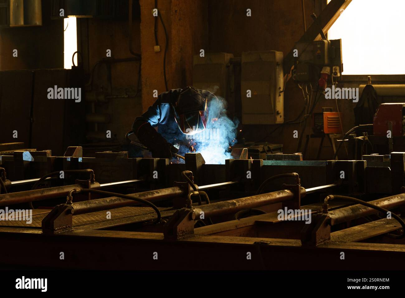 A dedicated craftsman is focused on welding metal pieces in a well-lit ...