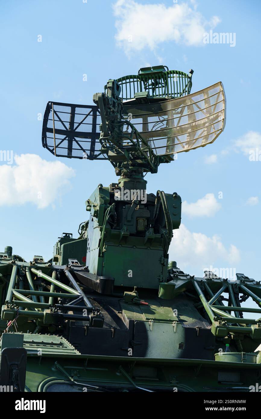 A military radar system stands tall against a backdrop of fluffy clouds ...
