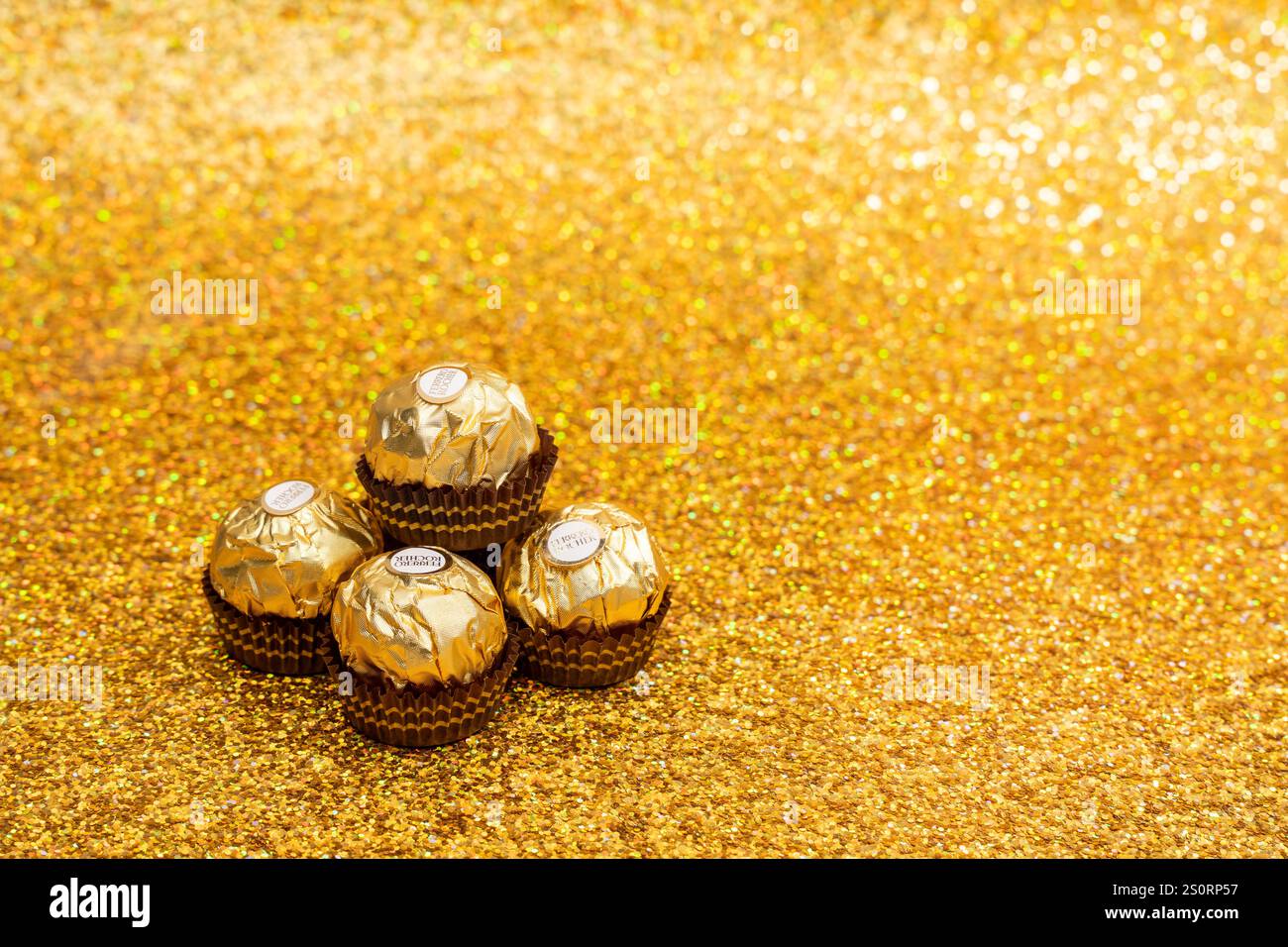 Ferrero Rocher chocolates in gold color sit on a gold background. The ...