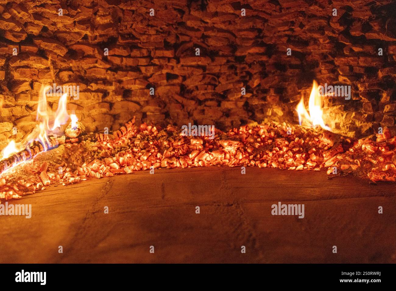 A close-up view of glowing coals and small flames inside a traditional ...