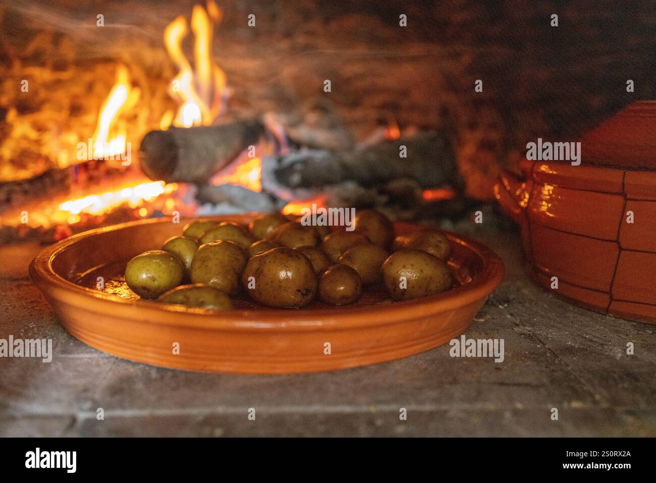 A rustic clay dish filled with potatoes baking inside a traditional ...