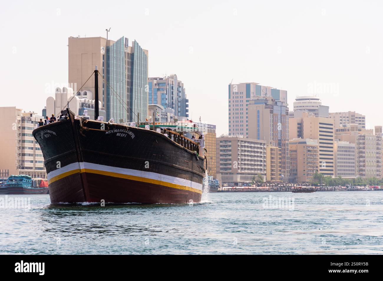 A large traditional dhow loaded with goods sails through Dubai Creek ...