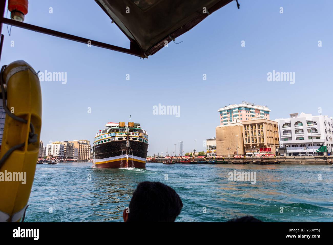 A large traditional dhow loaded with goods sails through Dubai Creek ...