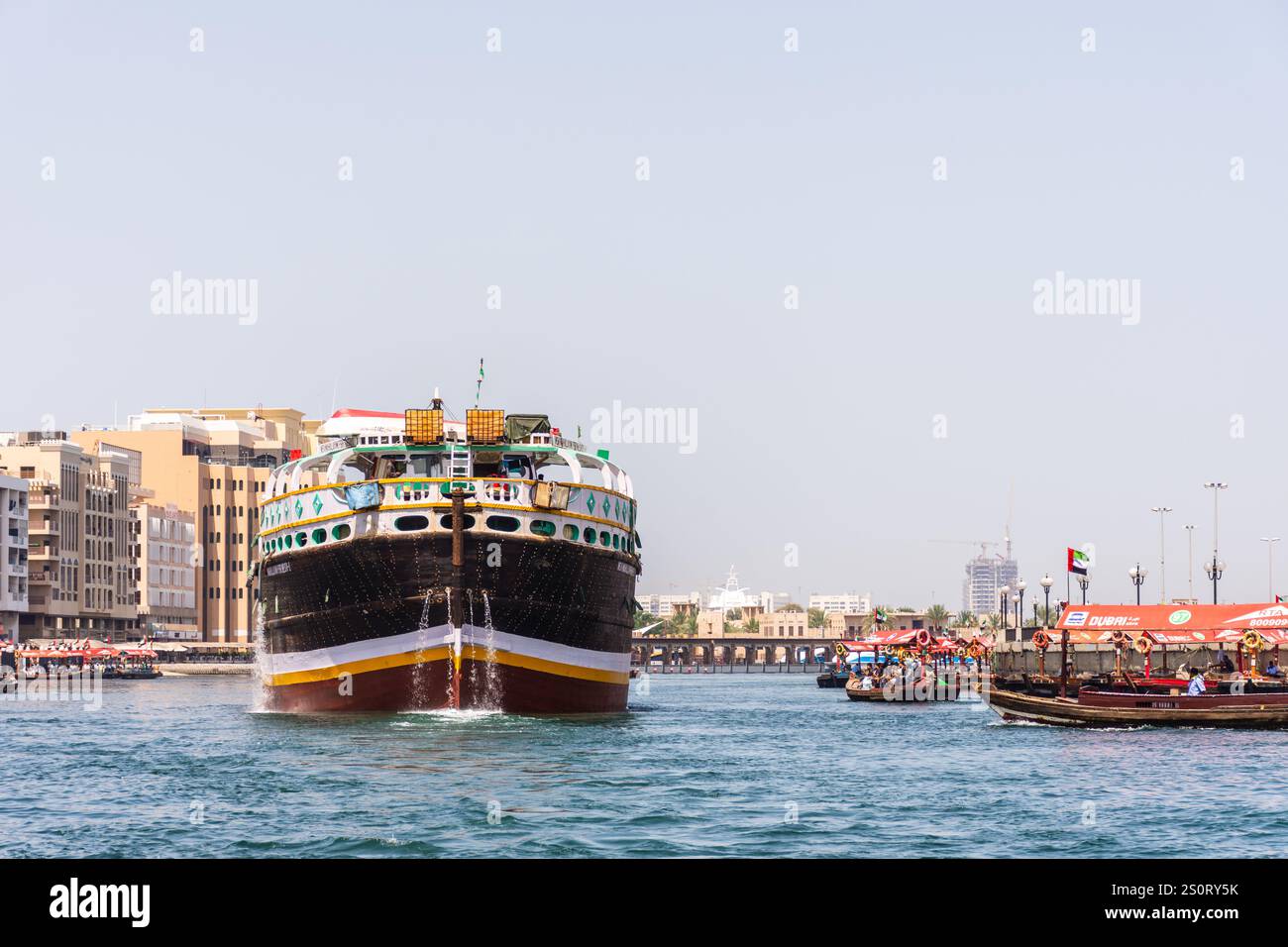 A large traditional dhow loaded with goods sails through Dubai Creek ...