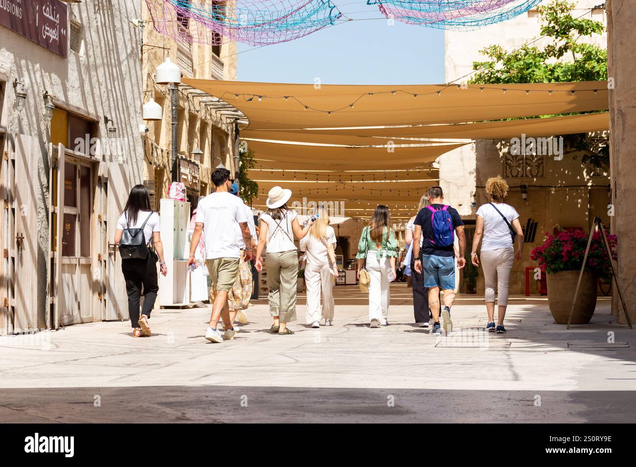 A group of tourists explores an outdoor market street in Al Seef Dubai ...