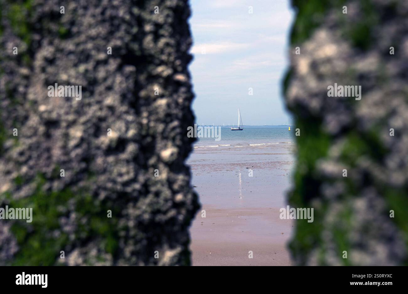 A serene view of a sailboat on the water, framed by two rocky ...