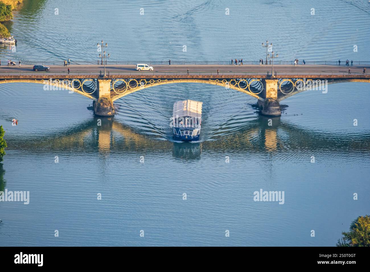 Tourist boat cruising under the historic Triana Bridge over the ...