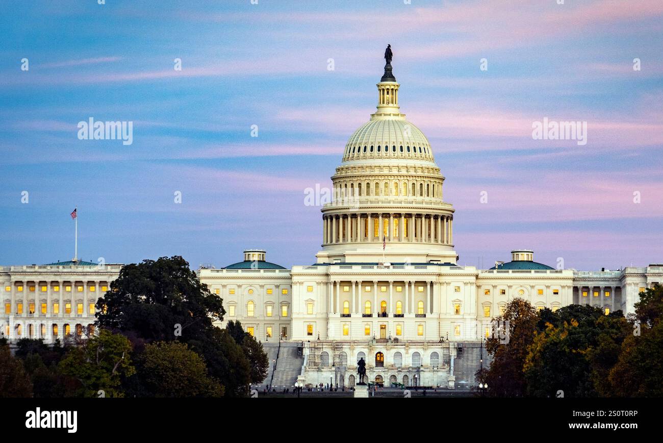 The United States Capitol building at dusk, illuminated against a ...