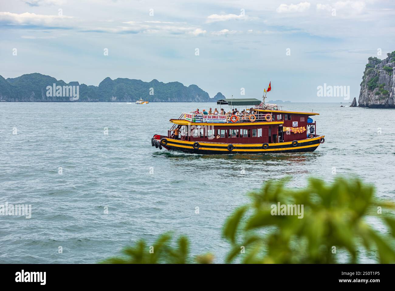 Cruise boat sailing among the rocks of Cat Ba island. A tour boat with ...