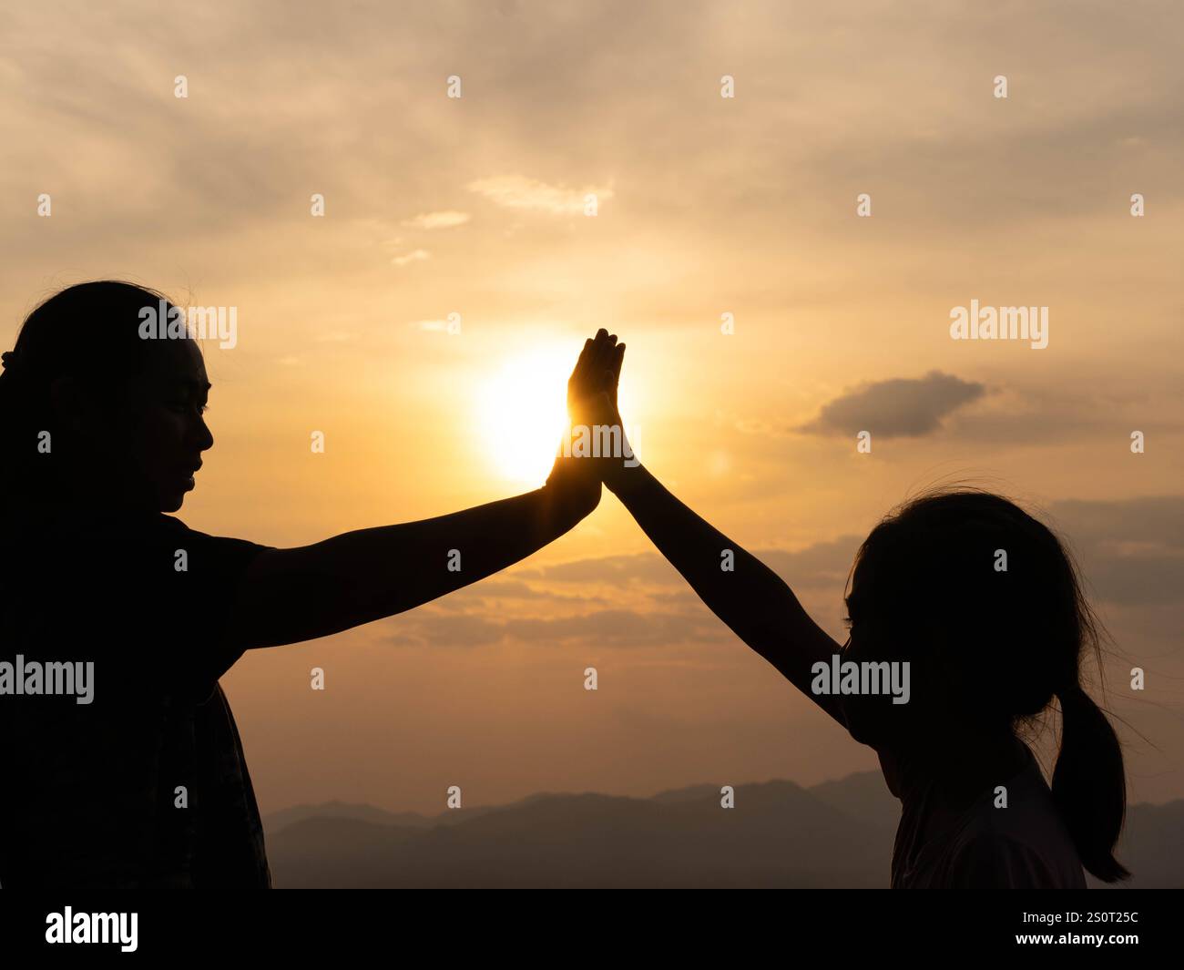 Happy mother and daughter walking on green grass in spring meadow. Mother and daughter holding ...