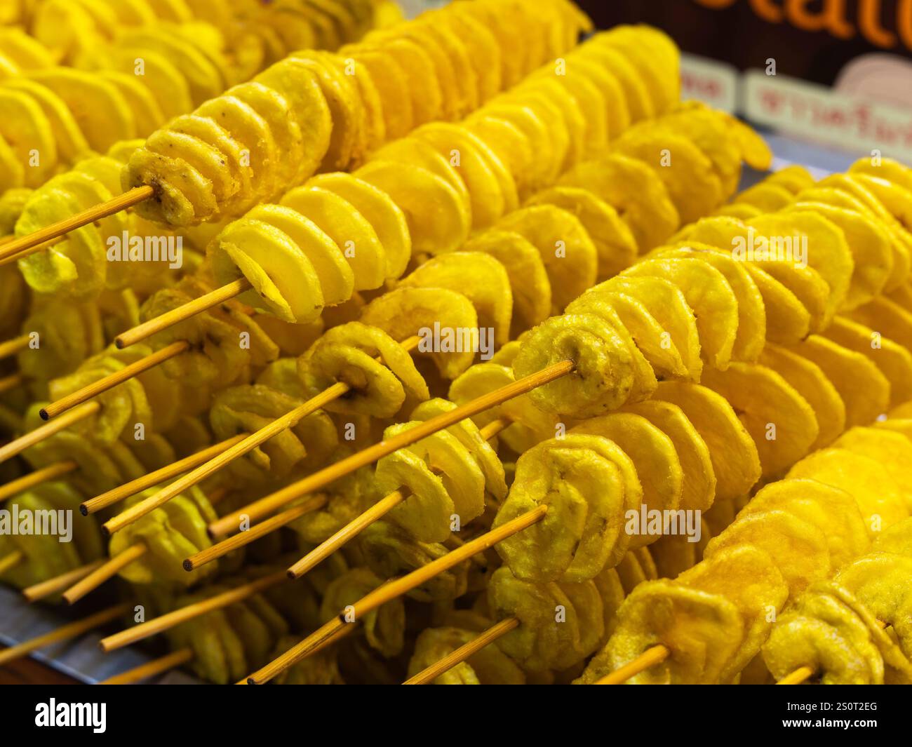 Spiral potatoes fried on a stick on a tray at a night market. Asian ...