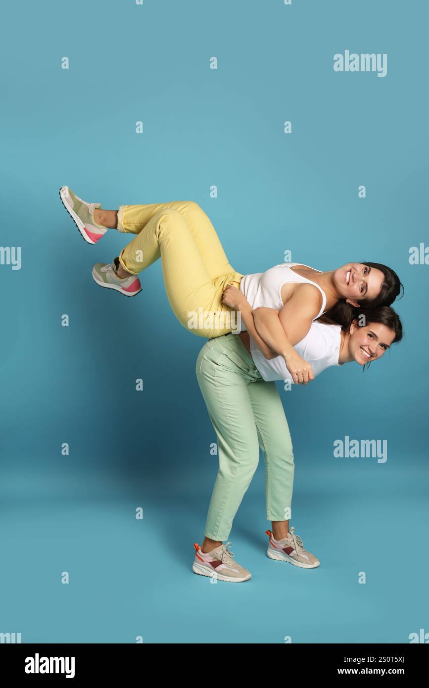 Beautiful twin sisters having fun on light blue background Stock Photo ...