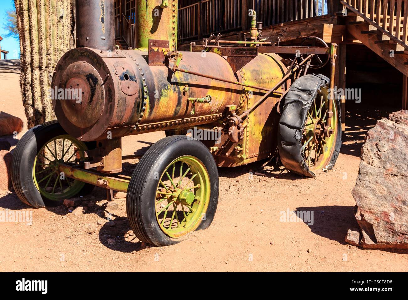 An old, rusted steam engine sits in the desert. The engine is ...