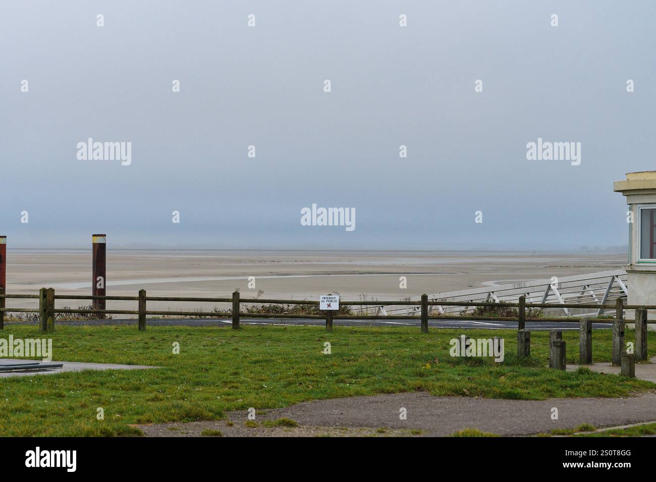 Coastal landscape with low tide and cloudy sky viewed from a grassy ...