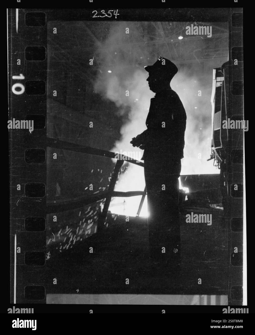 Title [Steel worker standing in mill with smelter in the background, in ...