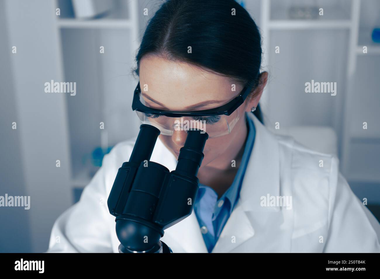 In a modern lab, a dedicated female scientist analyzes samples under a ...